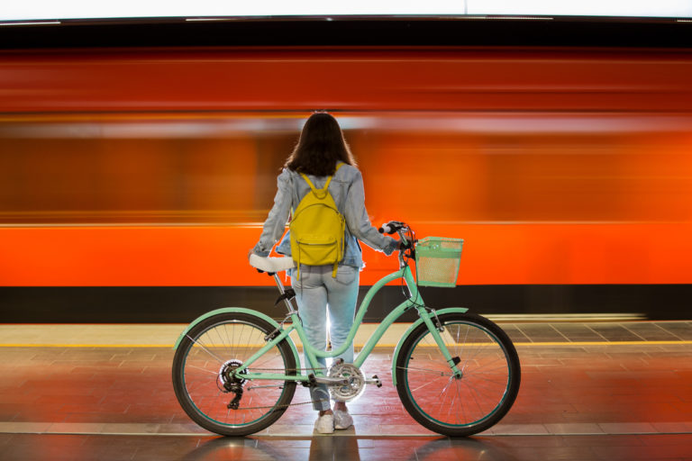 Teenager girl in jeans with bike standing on metro station | 2050Today